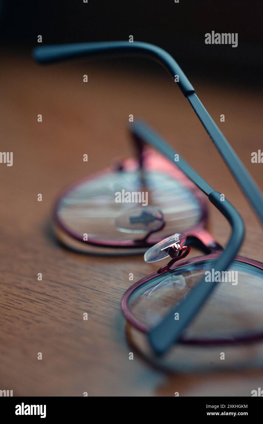 pair of varifocal spectacles laying face down on faux wood surface ...