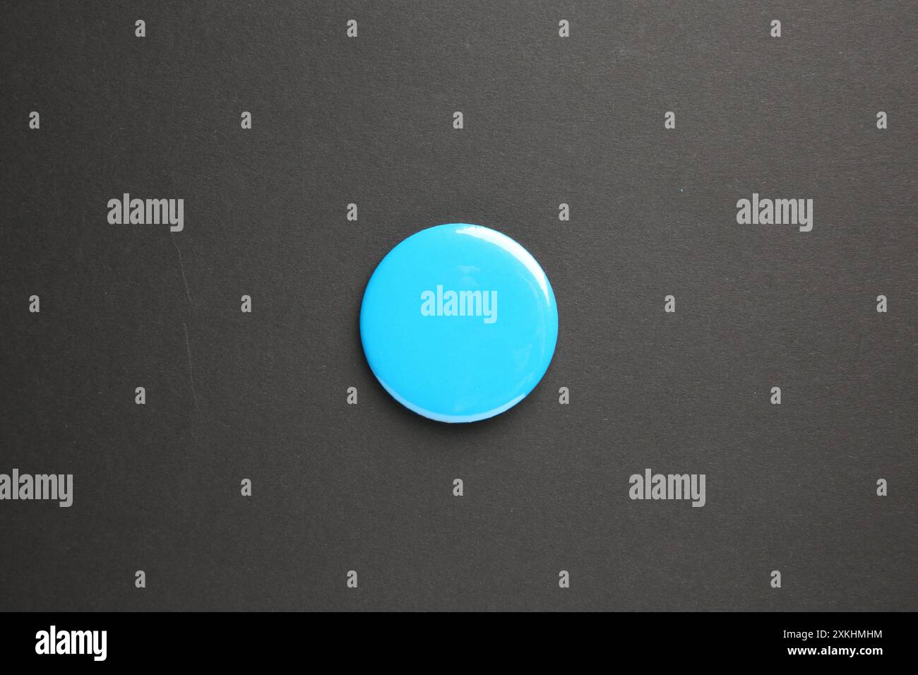 Blank light blue button badge on black background, top view. Mockup for ...