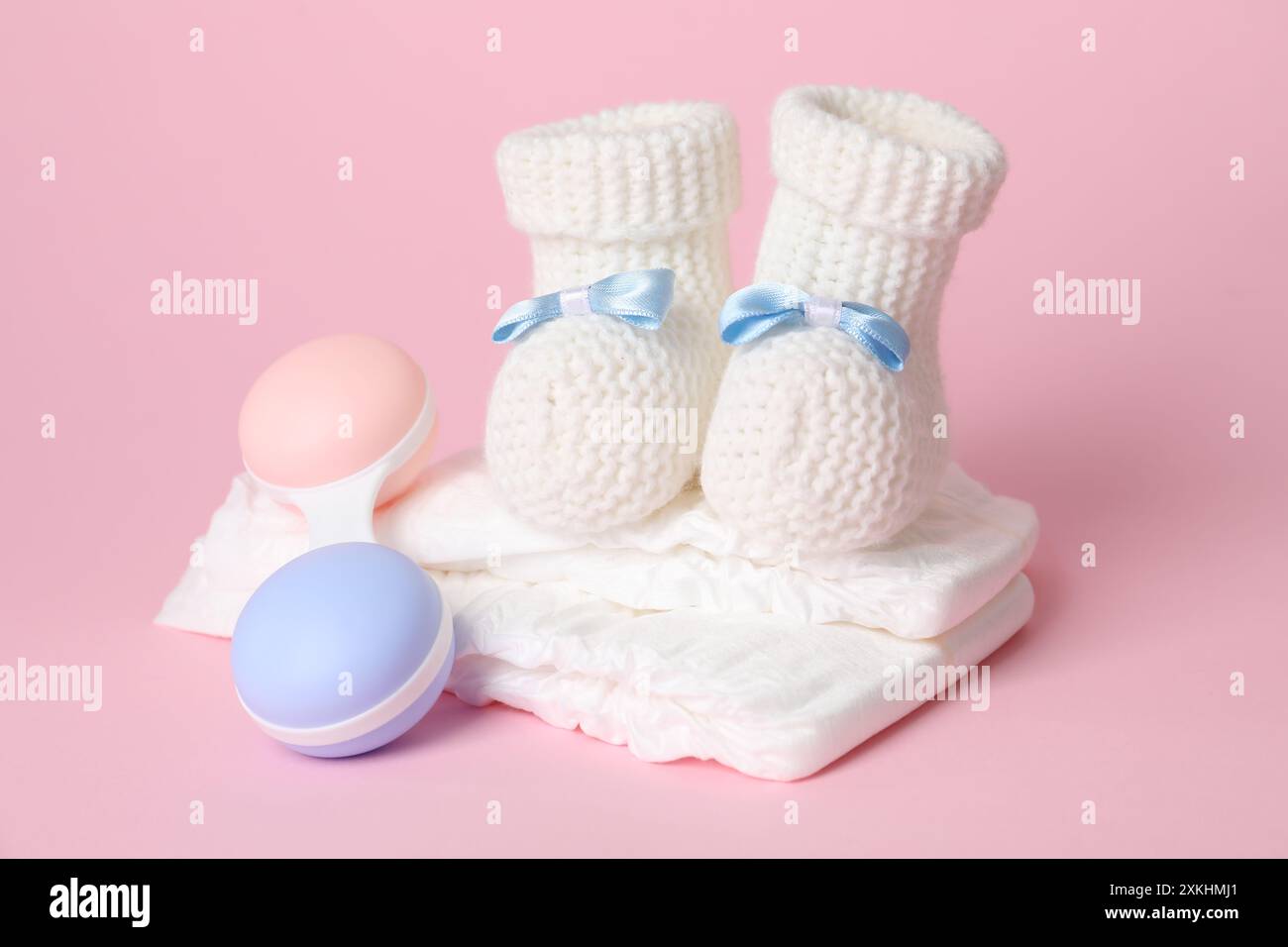 Baby rattle, booties and diapers on pink background Stock Photo - Alamy