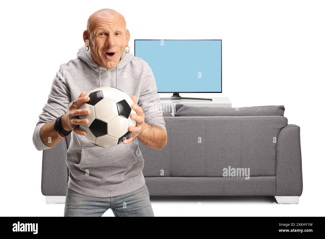 Excited bald man holding a football in front of tv and sofa isolated on ...