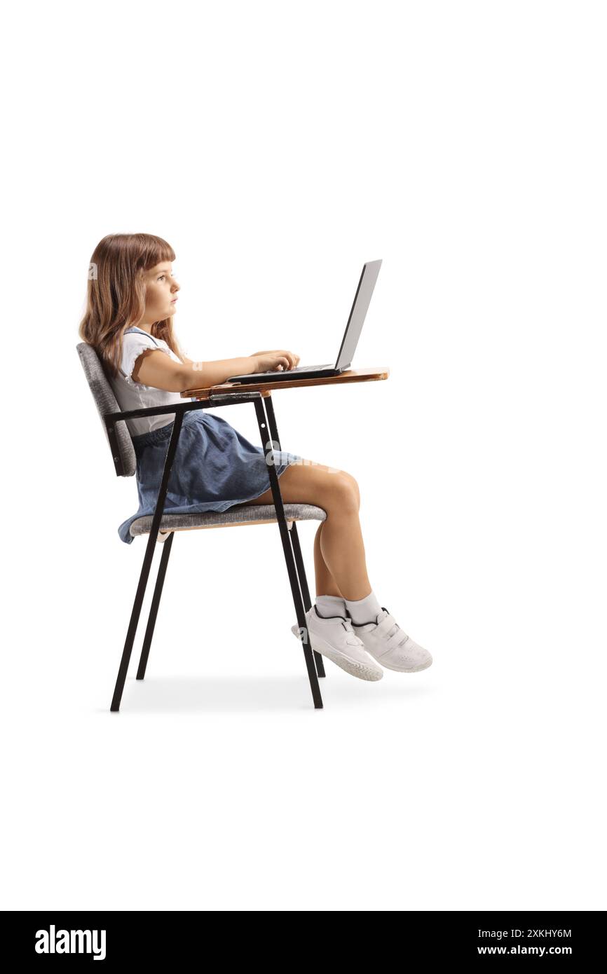 Little girl sitting in a school chair and using a laptop computer ...