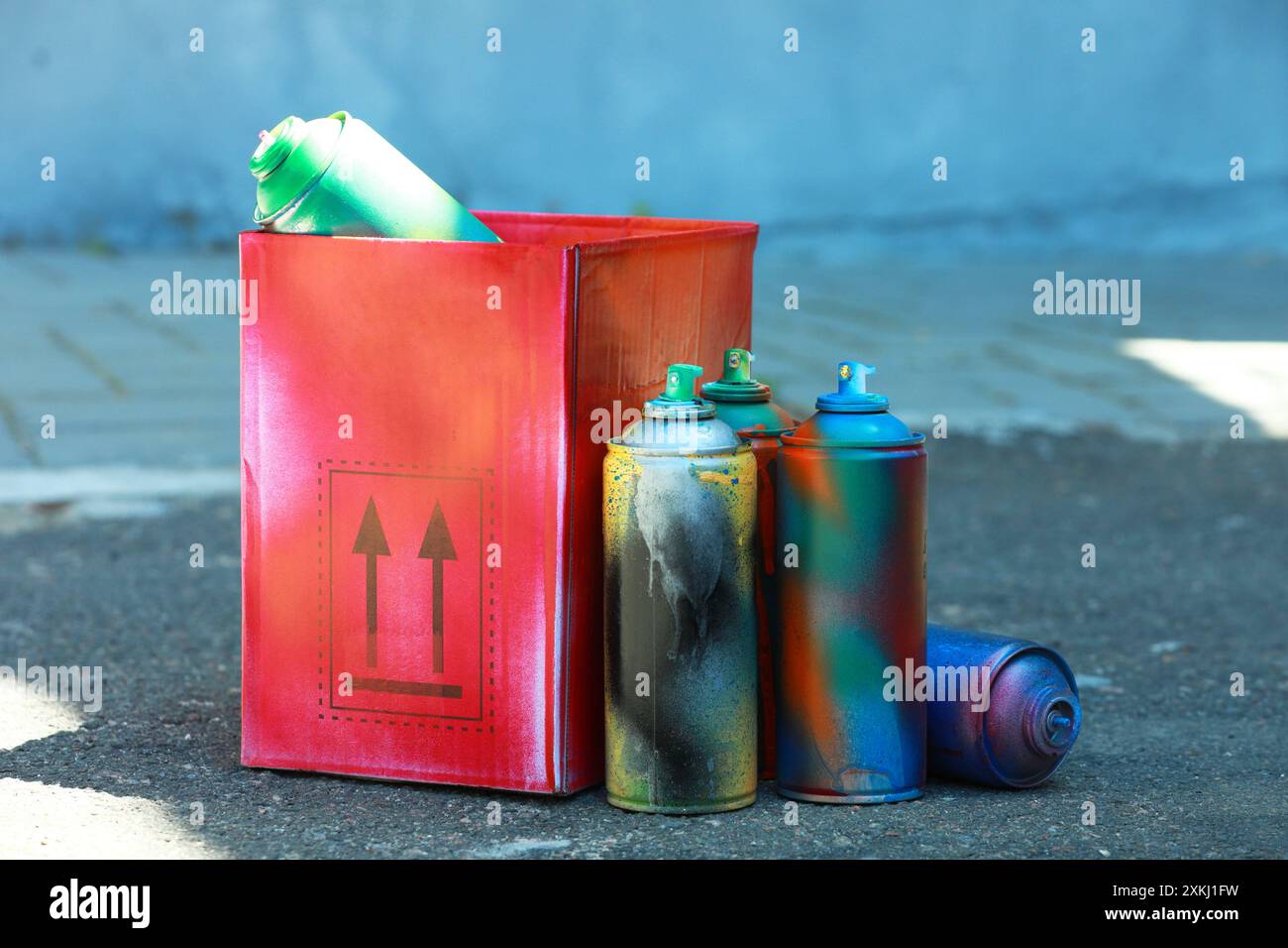 Many spray paint cans and red cardboard box outdoors Stock Photo - Alamy