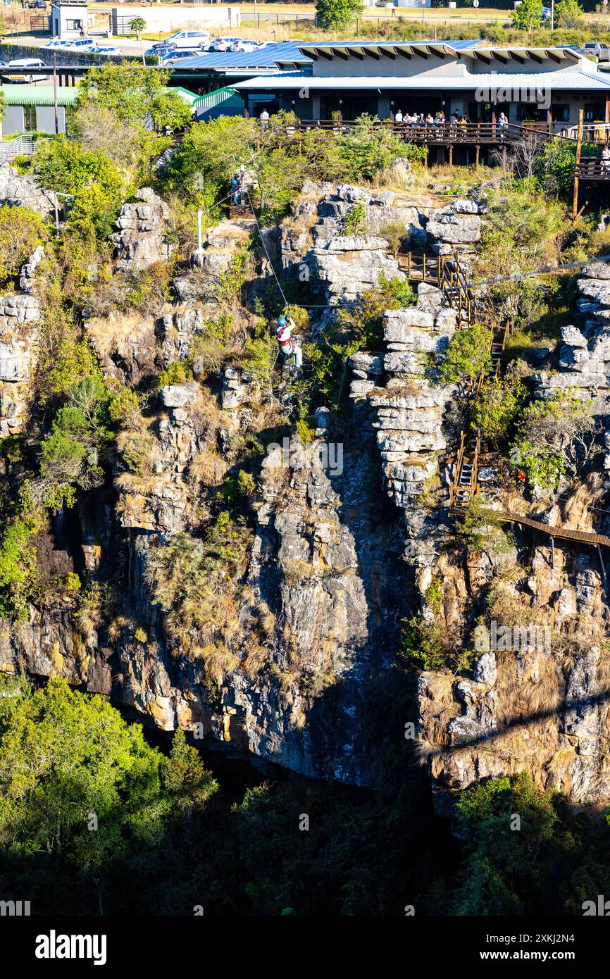 A woman ziplines across the Graskop Gorge. View of Graskop Gorge along ...