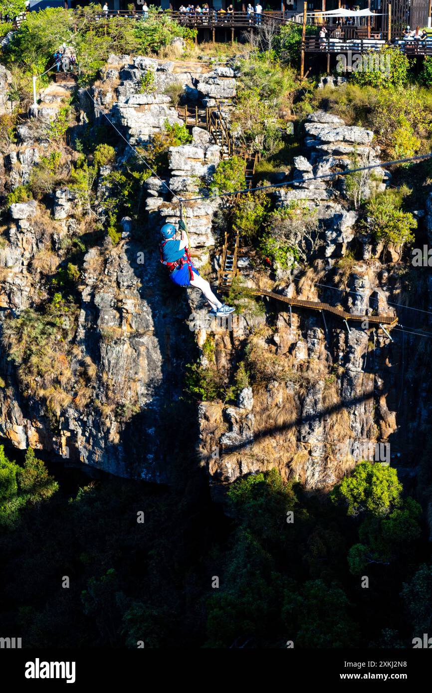 A man ziplines across the Graskop Gorge. View of Graskop Gorge along ...