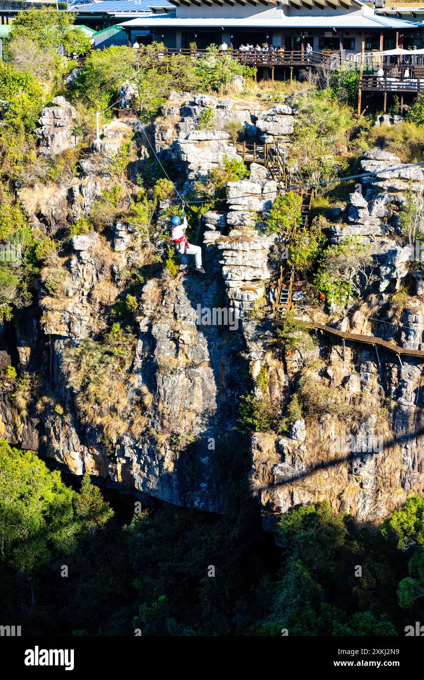 A woman ziplines across the Graskop Gorge. View of Graskop Gorge along ...