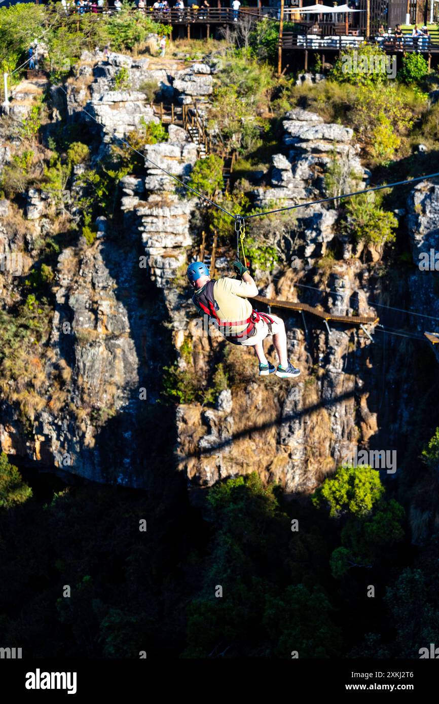 A man ziplines across the Graskop Gorge. View of Graskop Gorge along ...