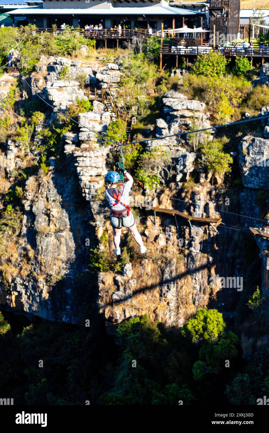 A woman ziplines across the Graskop Gorge. View of Graskop Gorge along ...