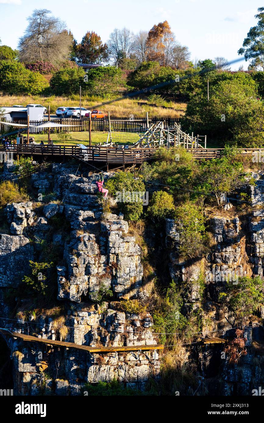 A girl ziplines across the Graskop Gorge. View of Graskop Gorge along ...