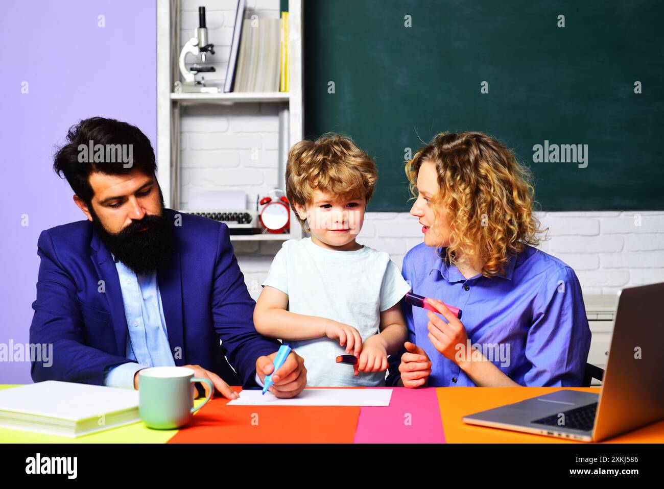 First day at school. Teachers man and woman helping child from primary ...