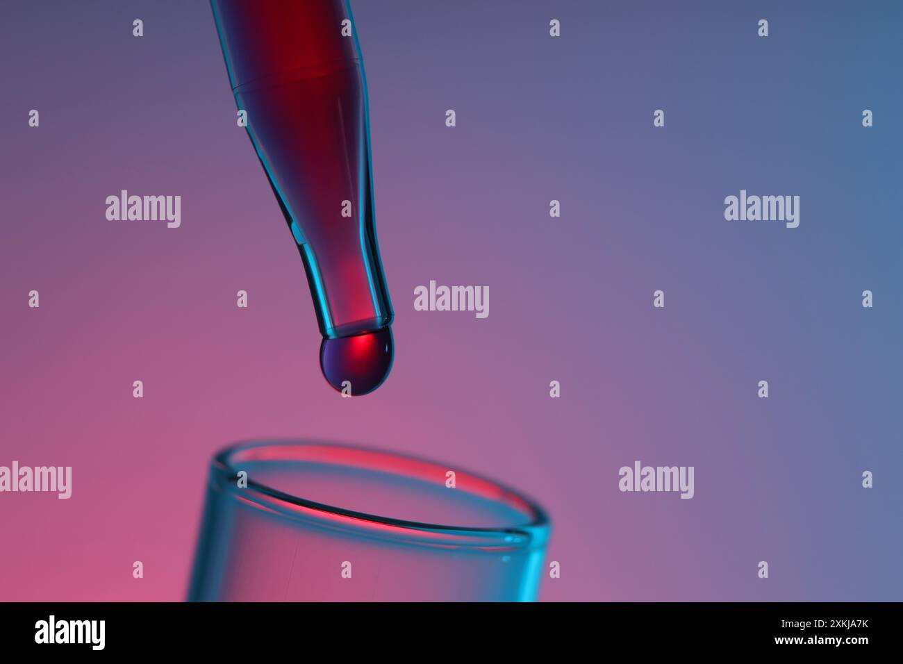 Dripping liquid from pipette into test tube on color background ...
