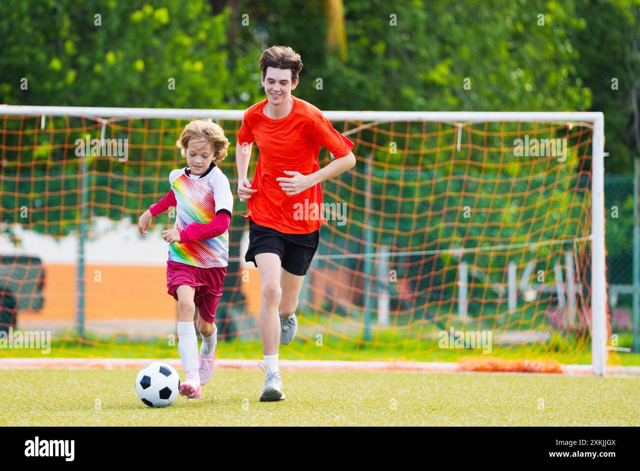 Child playing football. Kids play soccer on outdoor pitch. Little boy ...