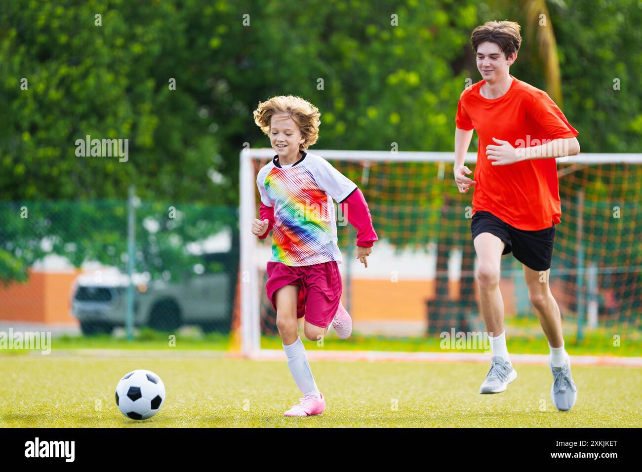 Child playing football. Kids play soccer on outdoor pitch. Little boy ...