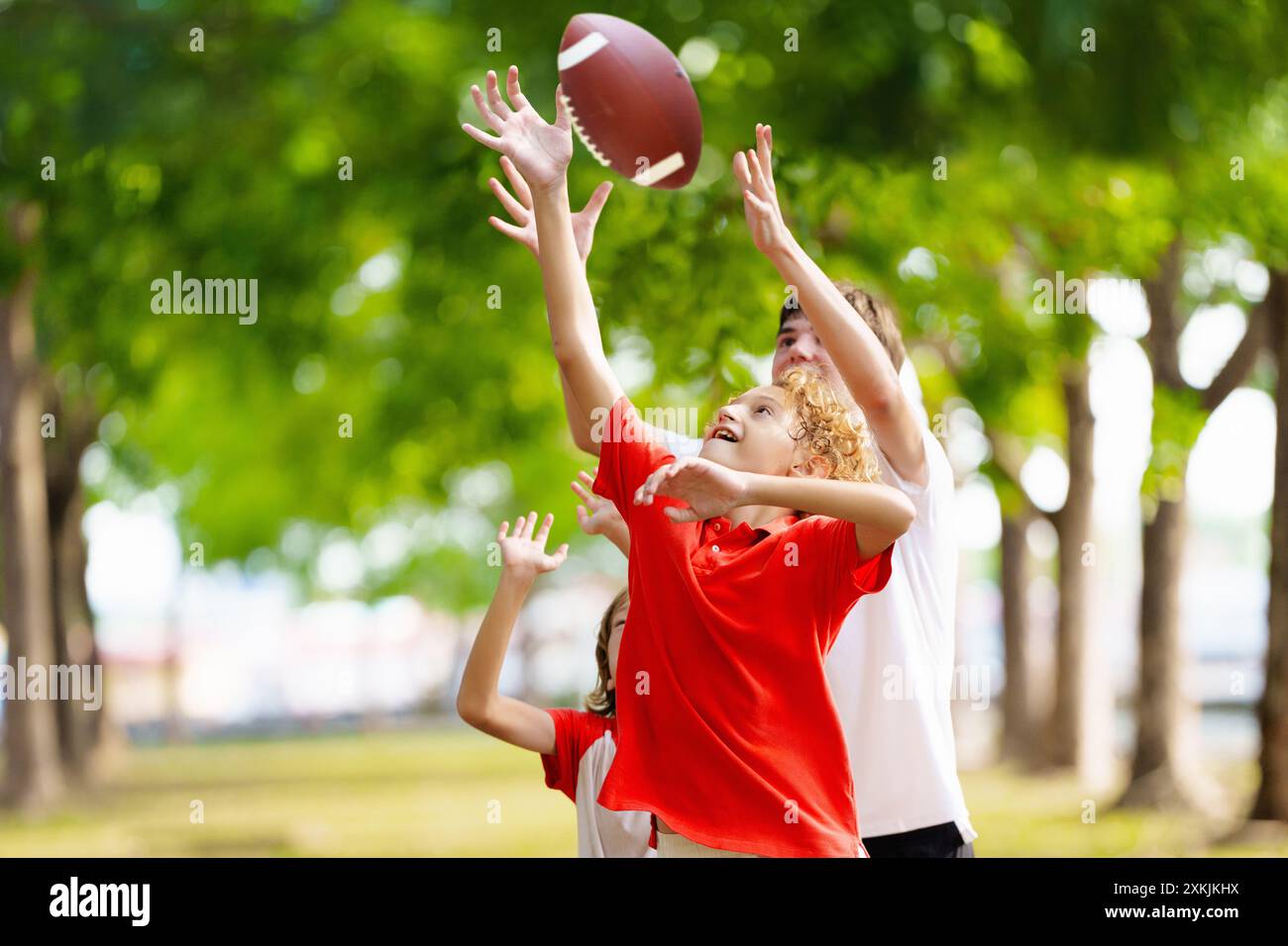 Family playing American football. Kids play rugby in sunny summer park ...