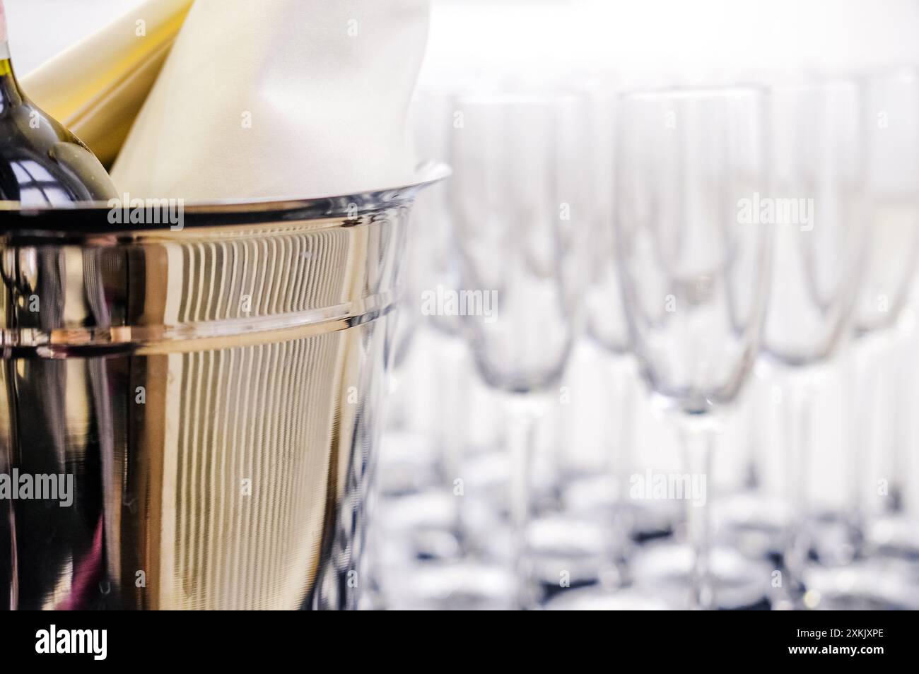Wine cooler with a wrapped bottle of alcohol and empty glasses arranged ...