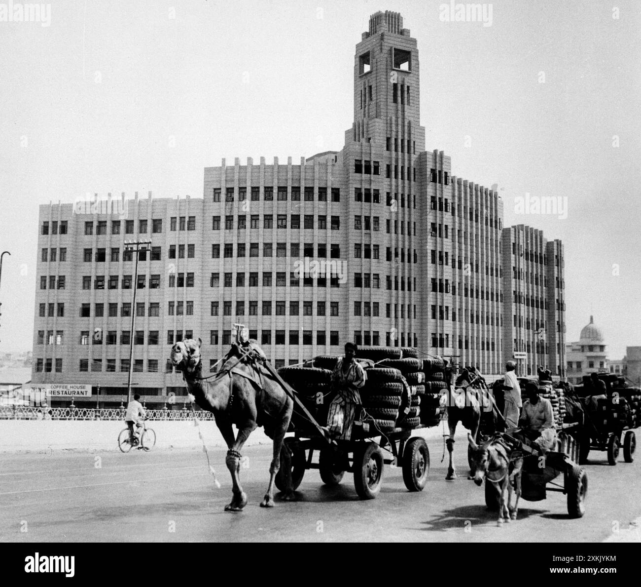 A train of camel-powered wagons laden with tires, crosses "Lovers ...