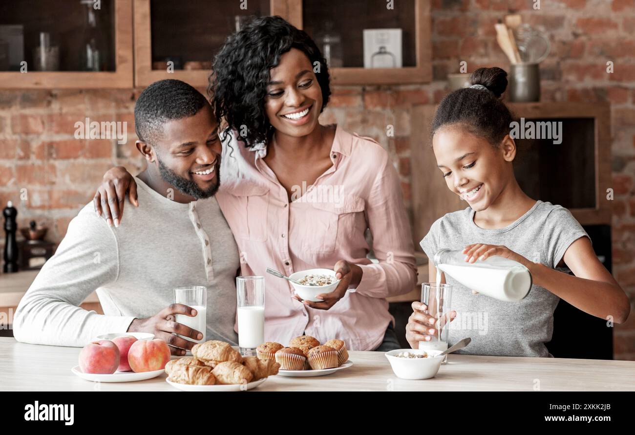Beautiful family drinking milk, eating sweets together at kitchen Stock ...