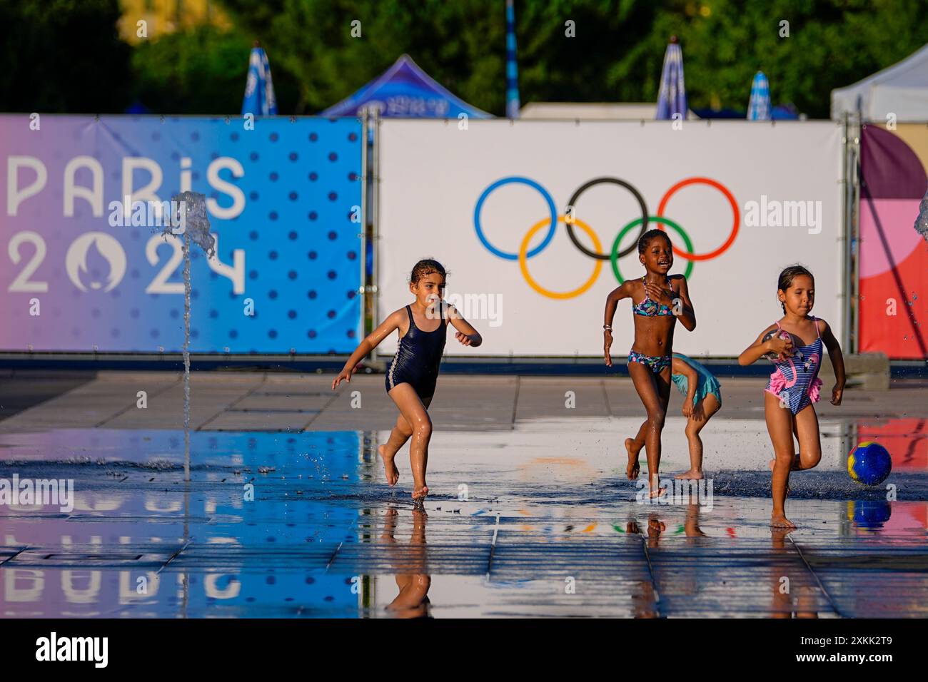 Children play at a splash fountain area near signage for the 2024 ...