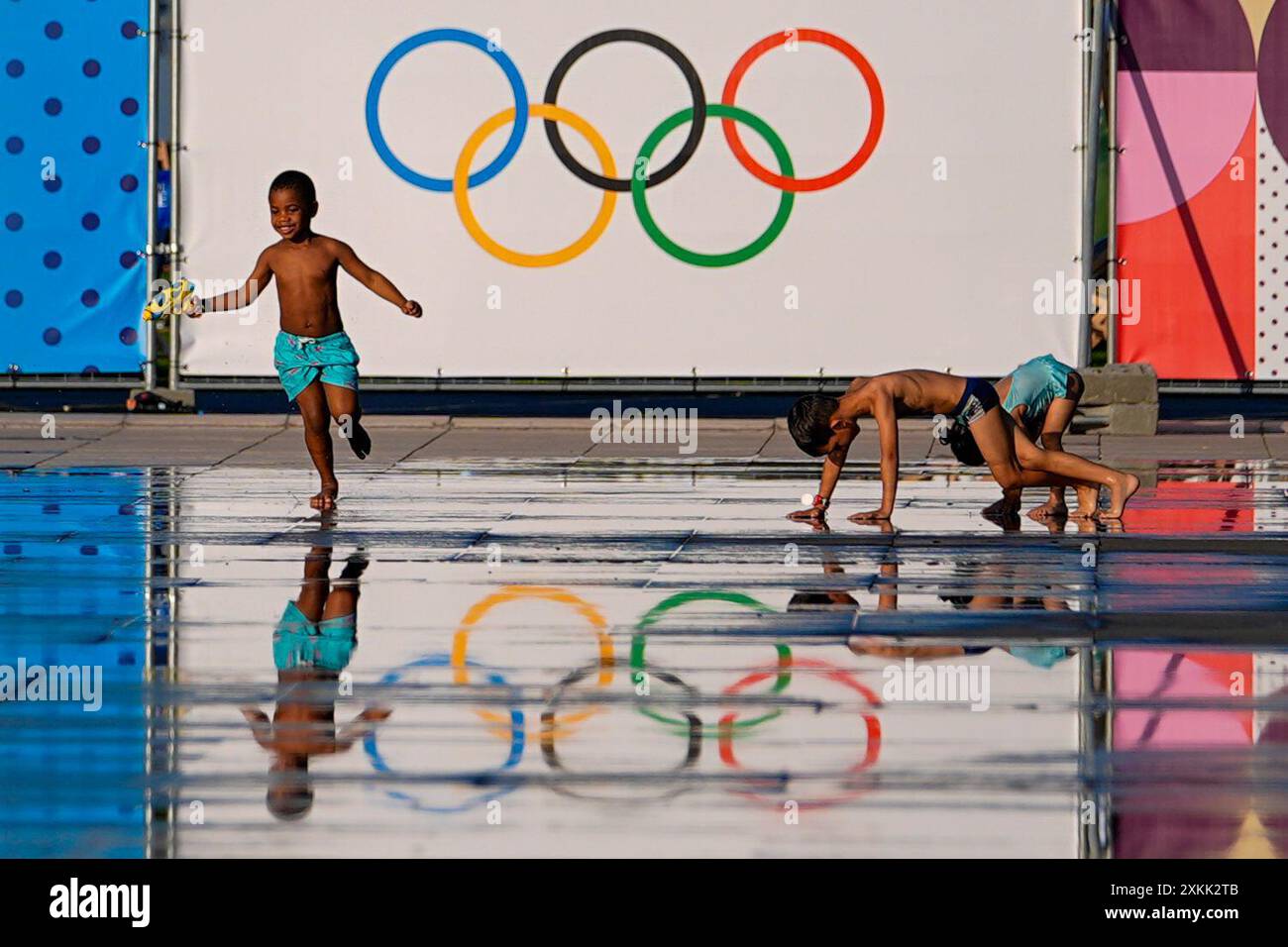 Children play at a splash fountain area near signage for the 2024 ...