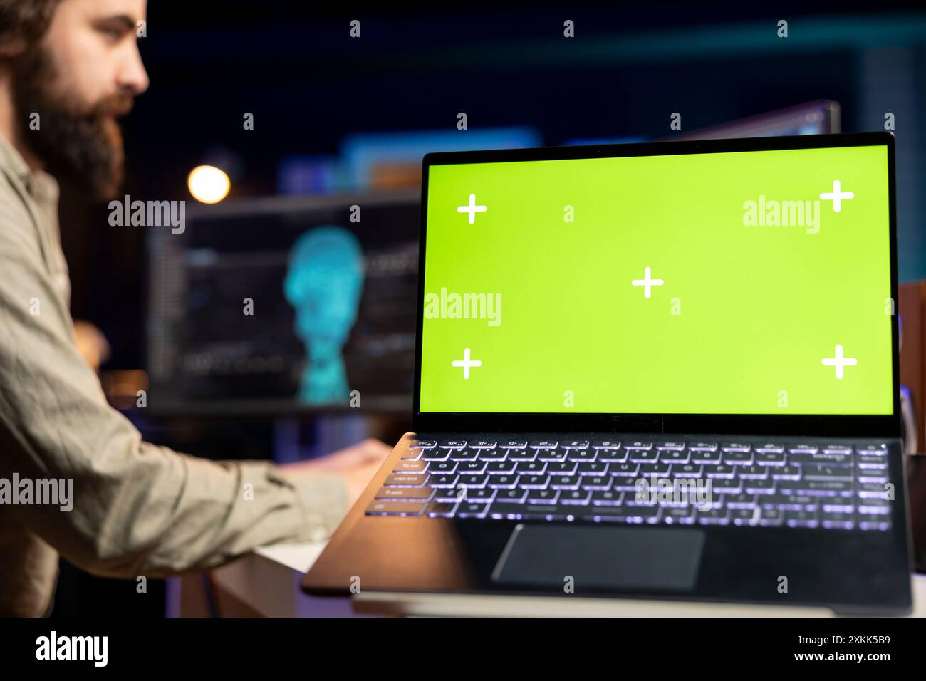 Focus on green screen laptop used by engineer wearing EEG headset in ...