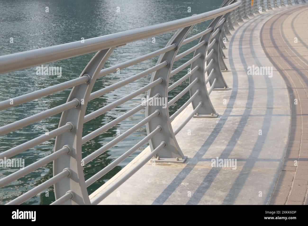 Curved metal railings on waterfront promenade. Pedestrian sidewalk with ...