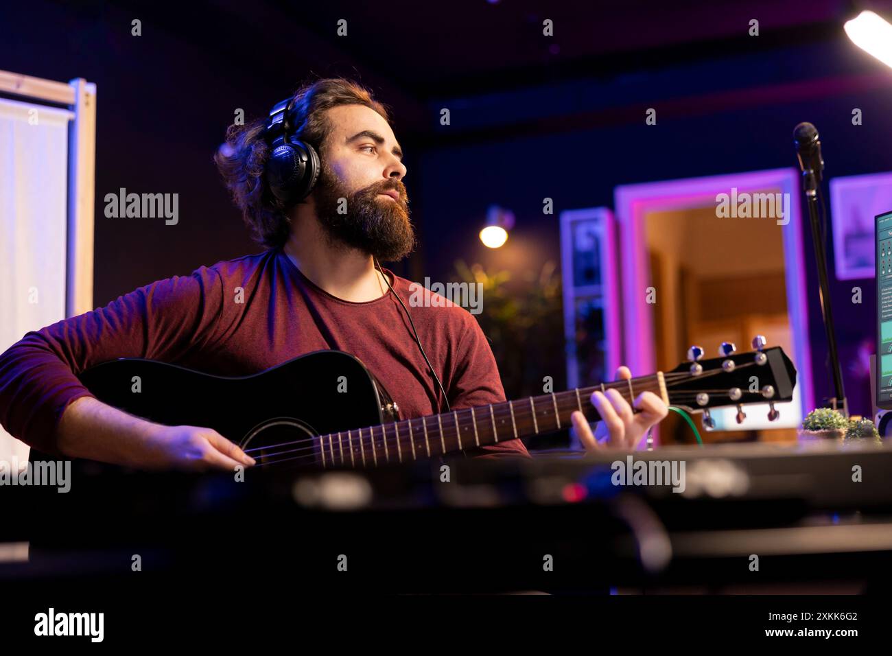 Musical artist recording acoustic guitar sounds for a new song in home ...