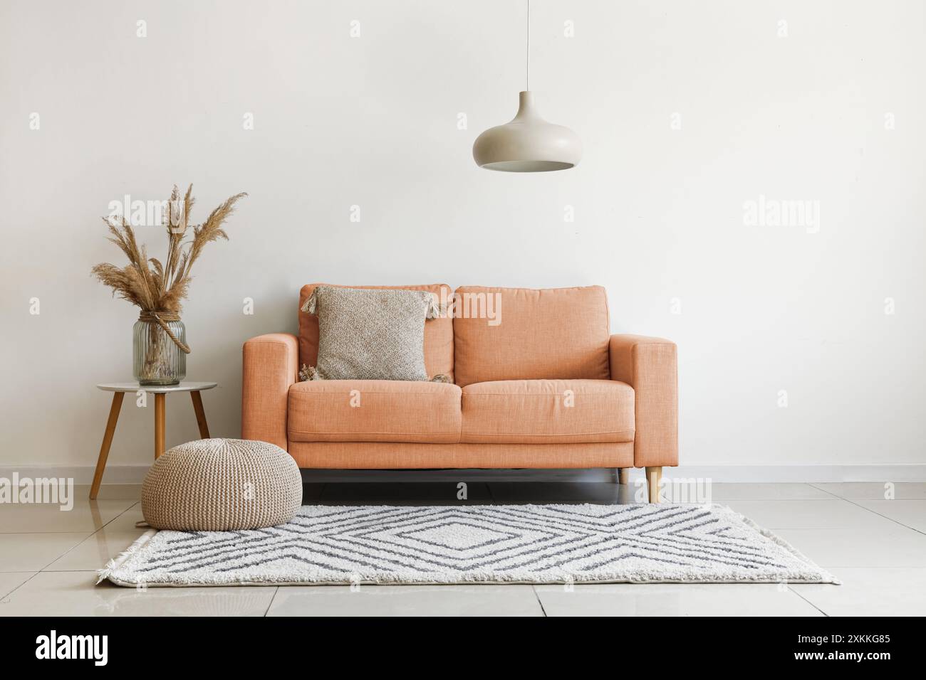 Peach sofa with pouf and table in light living room Stock Photo - Alamy