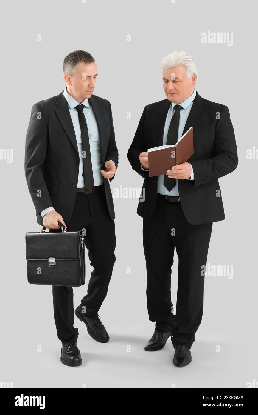 Mature brothers in suits with notebook on grey background Stock Photo ...