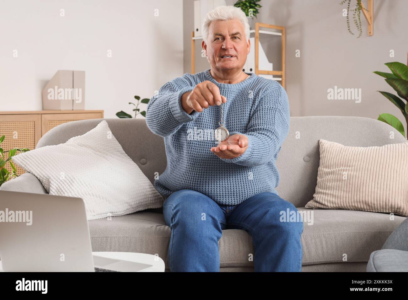 Male hypnotist with pocket watch sitting on sofa in office Stock Photo ...