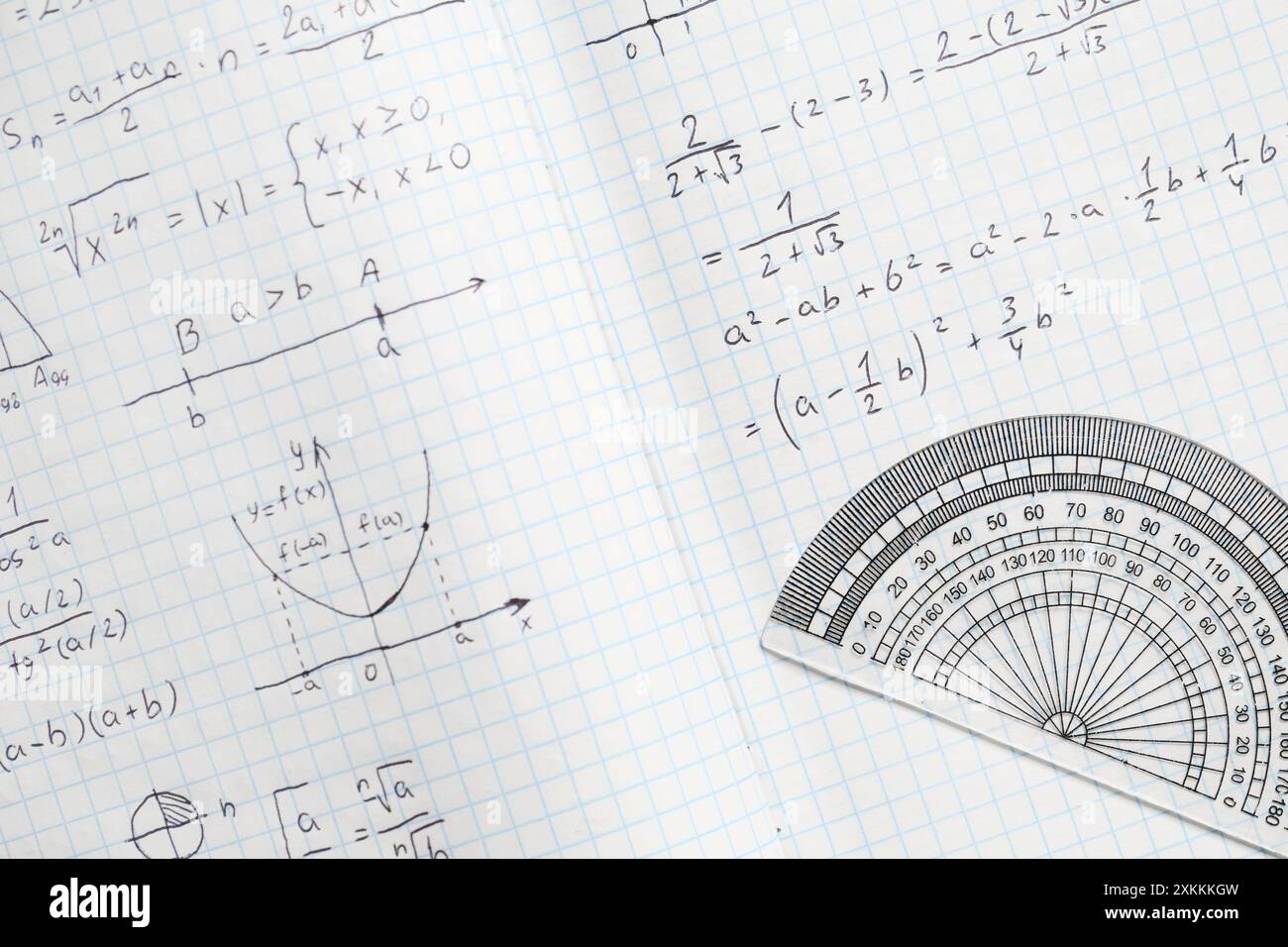 Copybook with handwritten maths formulas and semicircular protractor as ...