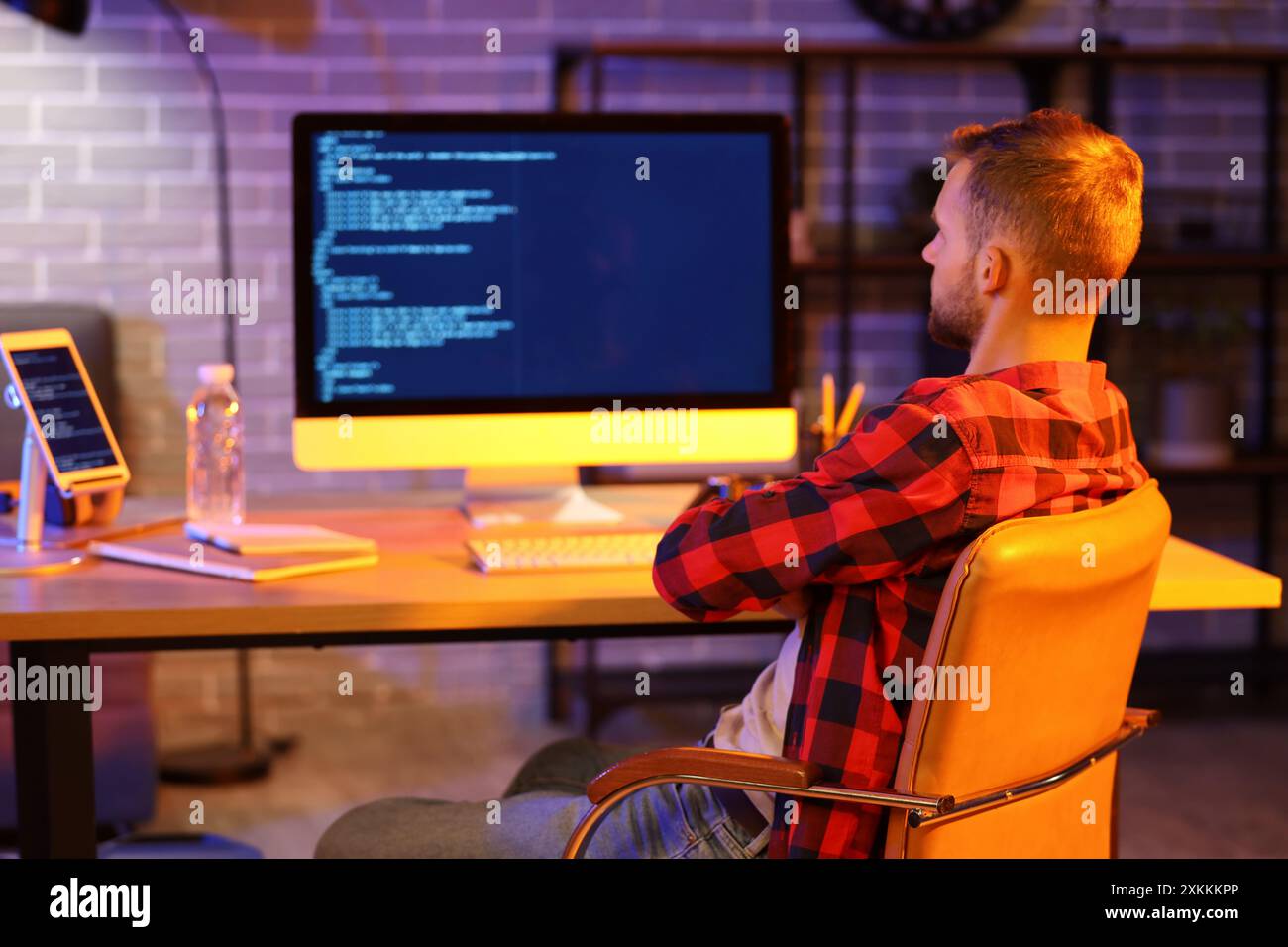 Male programmer sitting in office at night, back view Stock Photo - Alamy