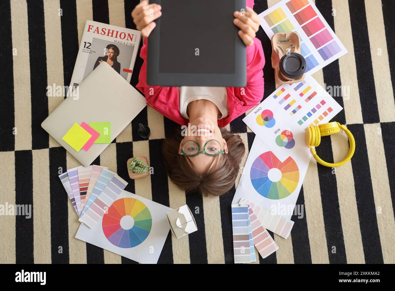 Female graphic designer with tablet and color palettes lying on carpet ...