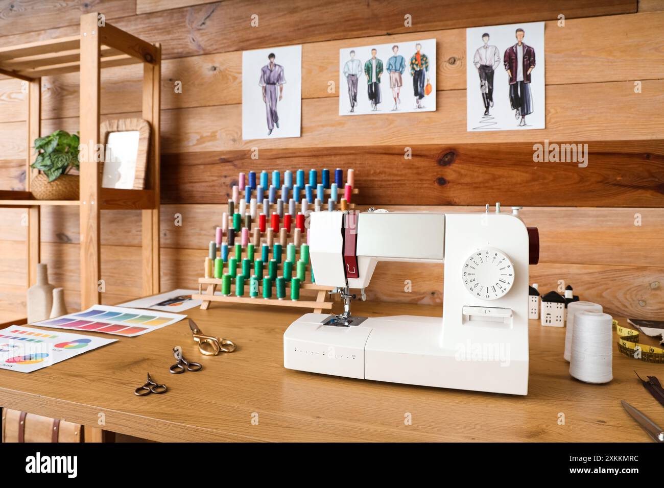 Tailor's workplace with sewing machine and thread spools in modern ...