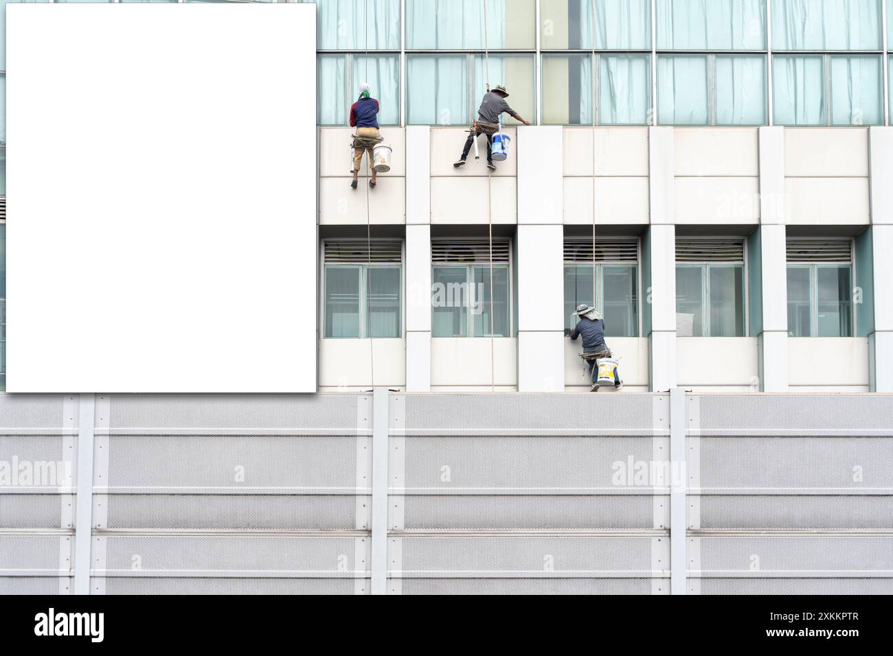 Blank poster on a building facade. Window washers at work. White empty ...