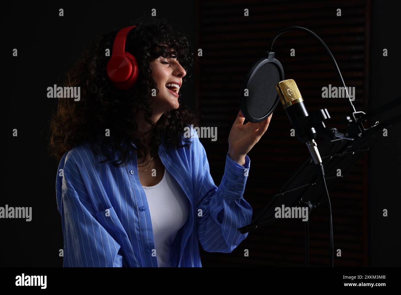 Vocalist with headphones singing into microphone in professional record ...