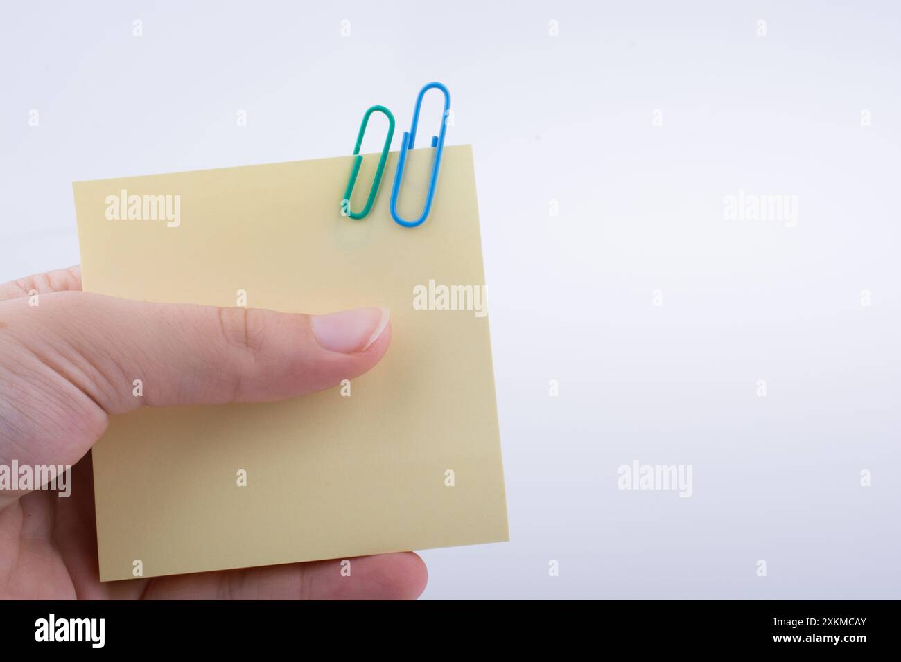 Hand holding a notepaper with paper clips on a white background Stock ...