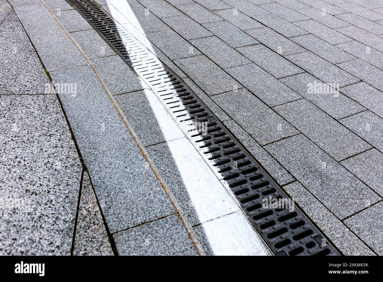 drainage grate on the road with white road marking crossing it Stock ...