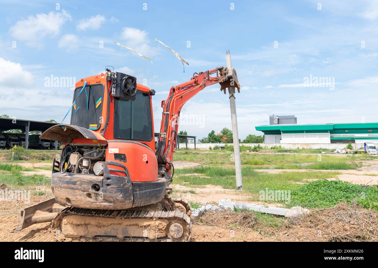 Small excavator lift pole move to hole for make fence in construction ...
