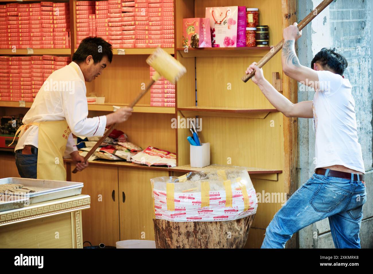 Chinese men with wooden mallets are crushing nuts to make sweets Stock ...