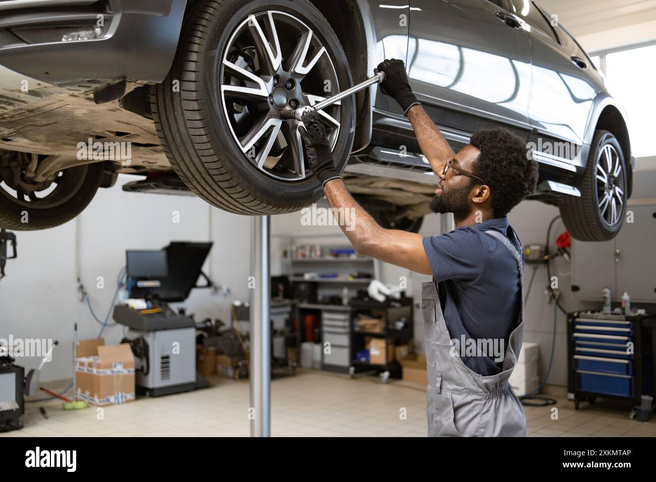 Mechanic working on car wheel in auto repair shop Stock Photo - Alamy