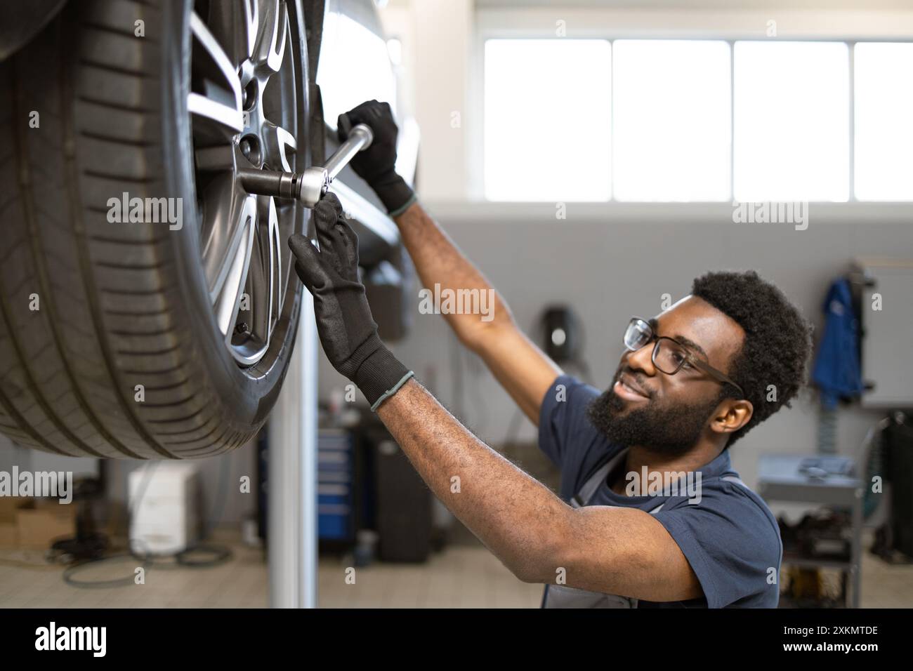 Mechanic working on car wheel in auto repair shop Stock Photo - Alamy