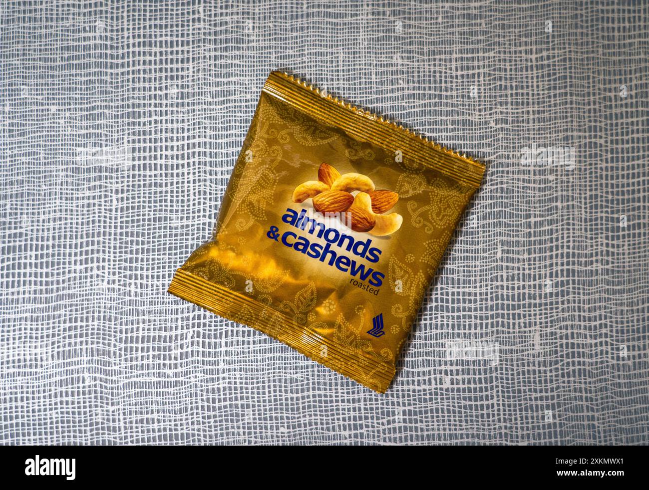 A packet of roasted Almonds and Cashews on textured background ...