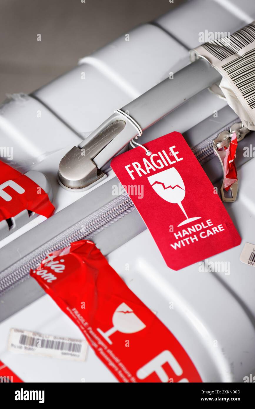 Closeup view of red luggage tag (Fragile) attached to suitcase Stock ...