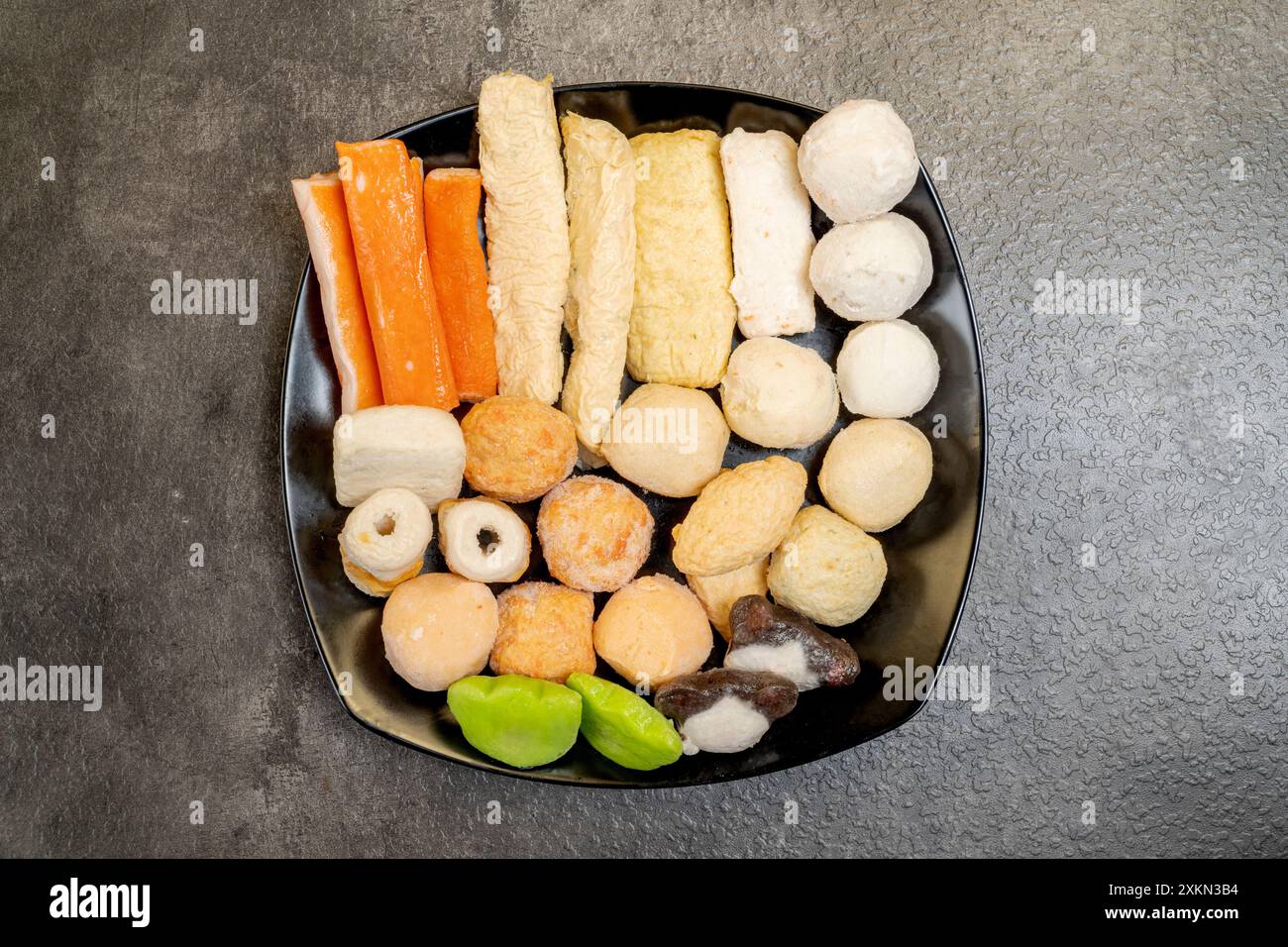 A black tray with a variety of food items including a crab and a green ...