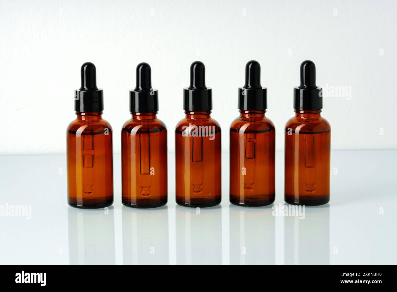 Row of various brown glass dropper bottles isolated on white background ...