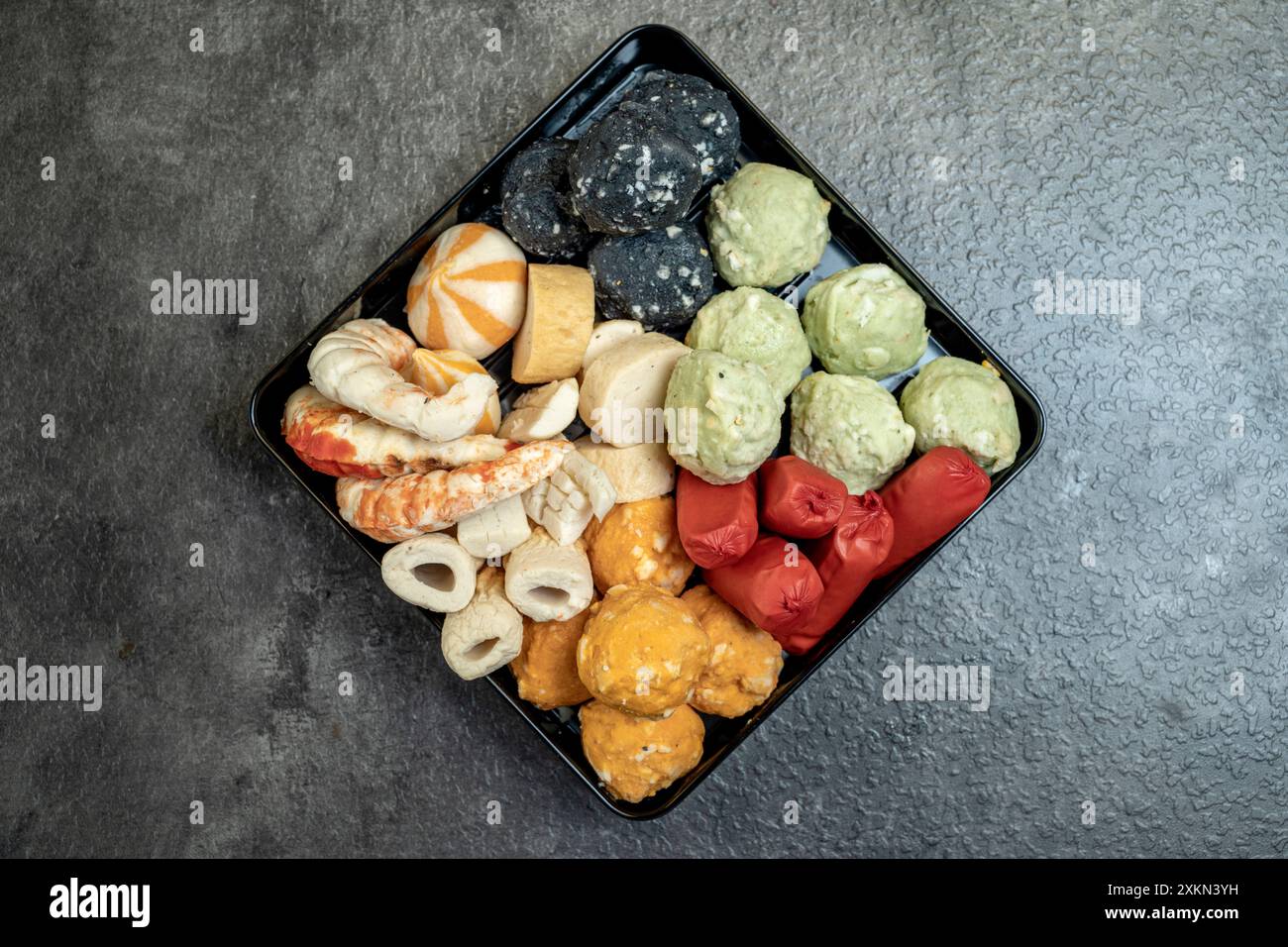 A black tray with a variety of food items including a crab and a green ...