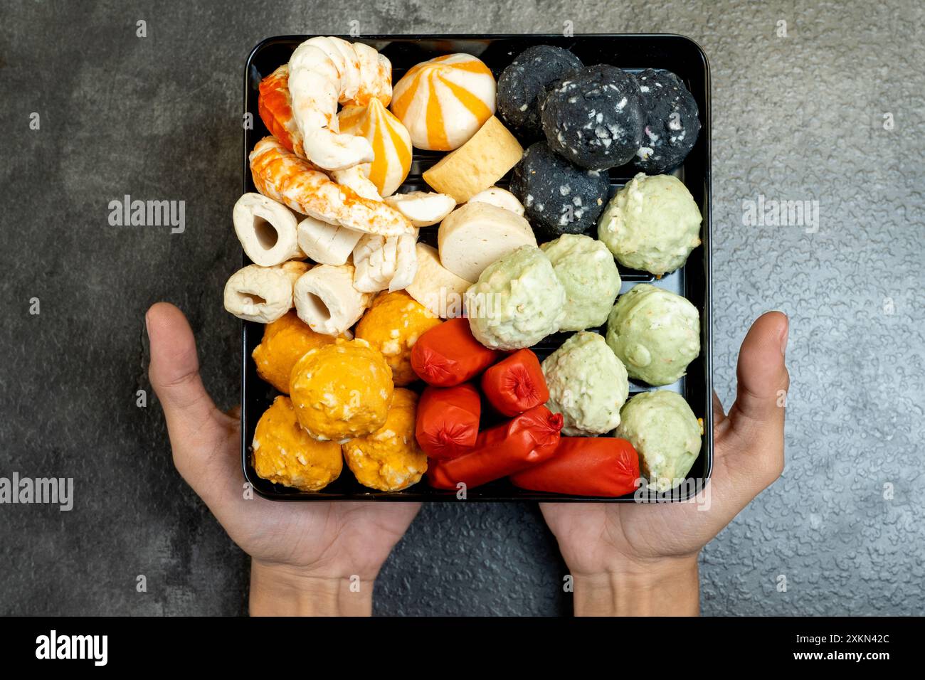 A person is holding a tray of assorted food items, including a variety ...