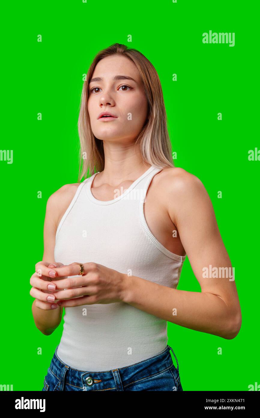 Young Woman in White Tank Top Looking Upward Against Green Screen Stock ...