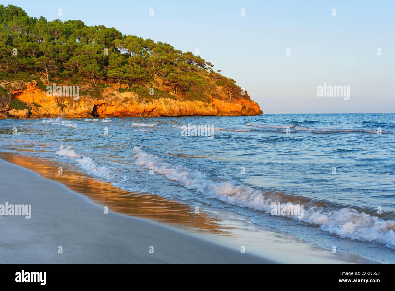 Gentle waves caress the sandy beach as vibrant cliffs rise in the ...