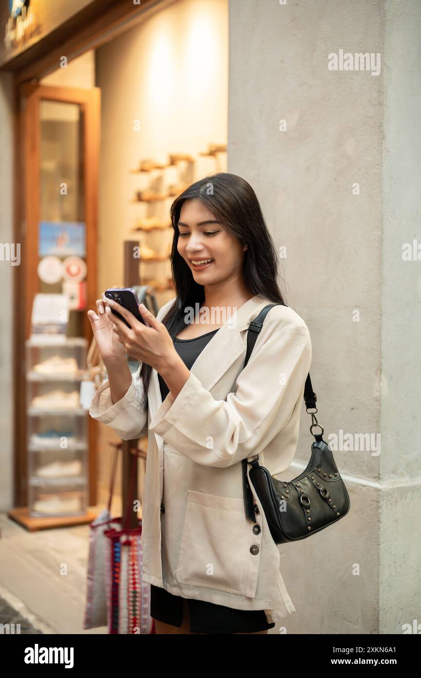 A confident, happy Asian woman in fashionable clothes is chatting or ...