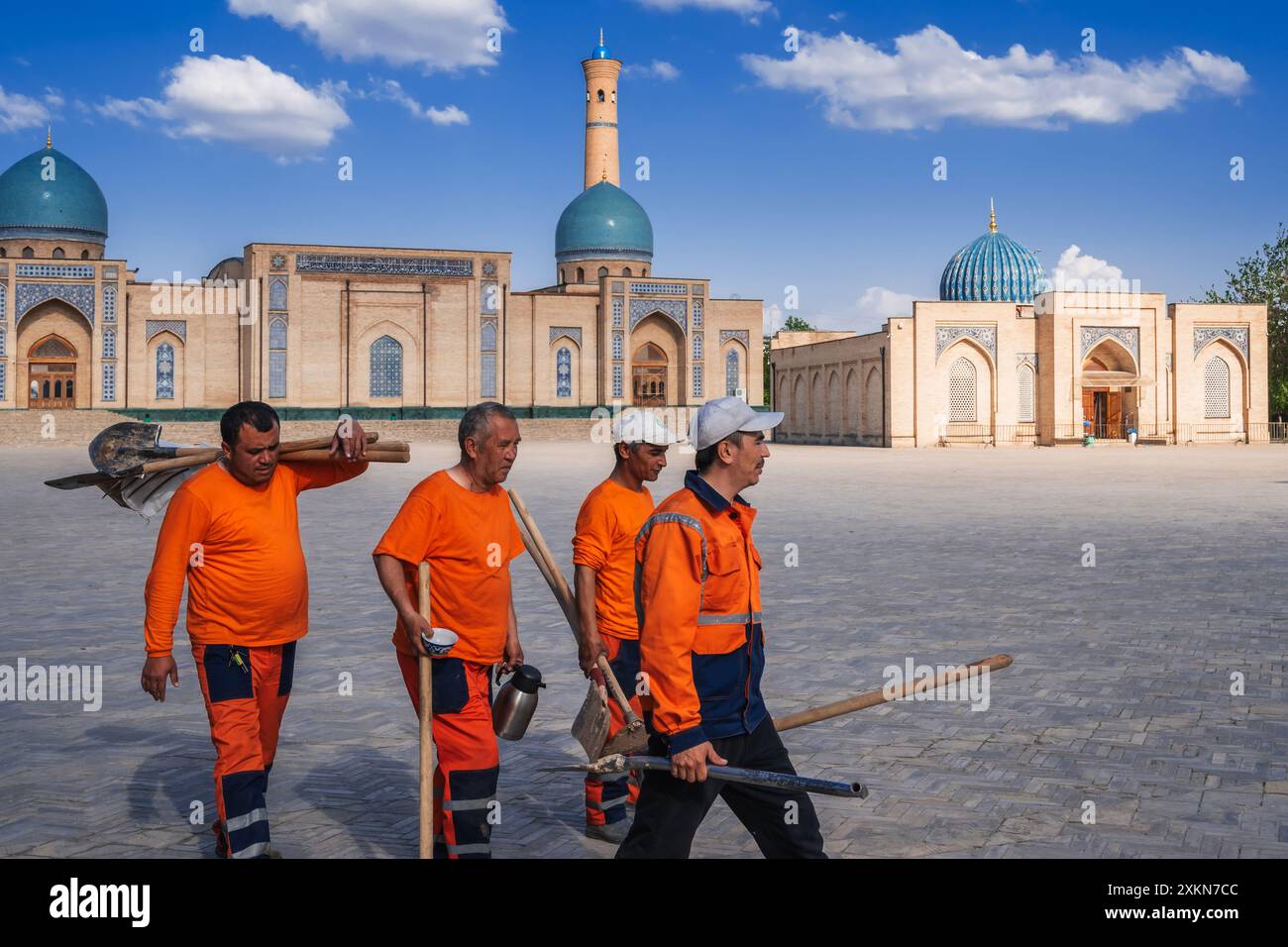 group of Uzbek male janitors in orange uniforms with shovels on the ...